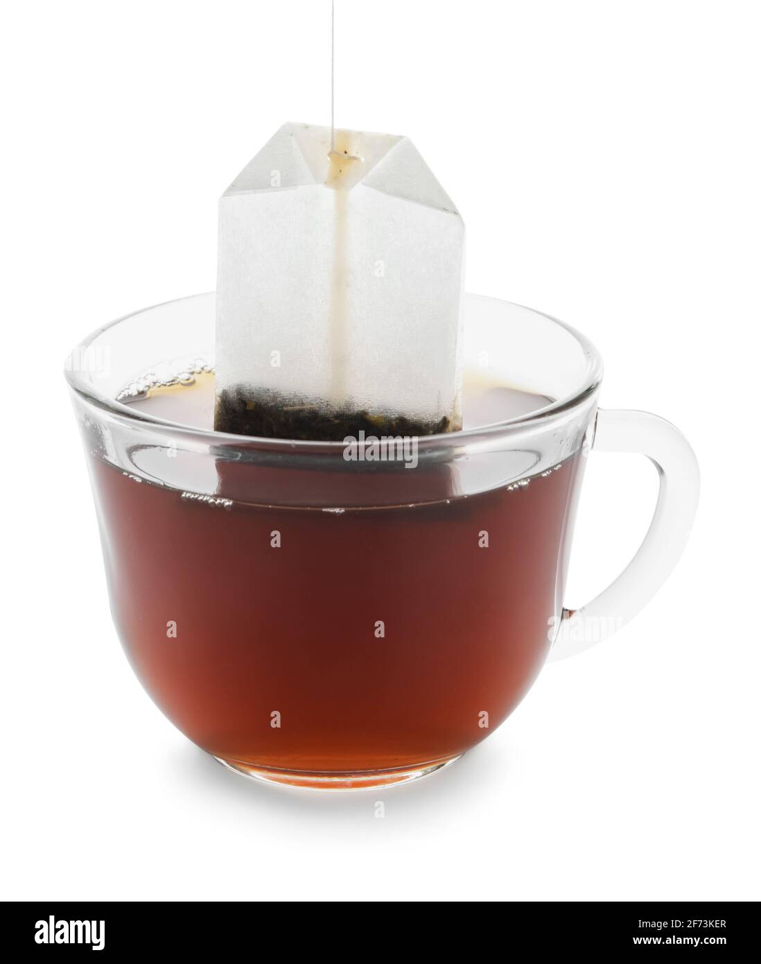 Taking tea bag out of glass cup with hot beverage on white background ...