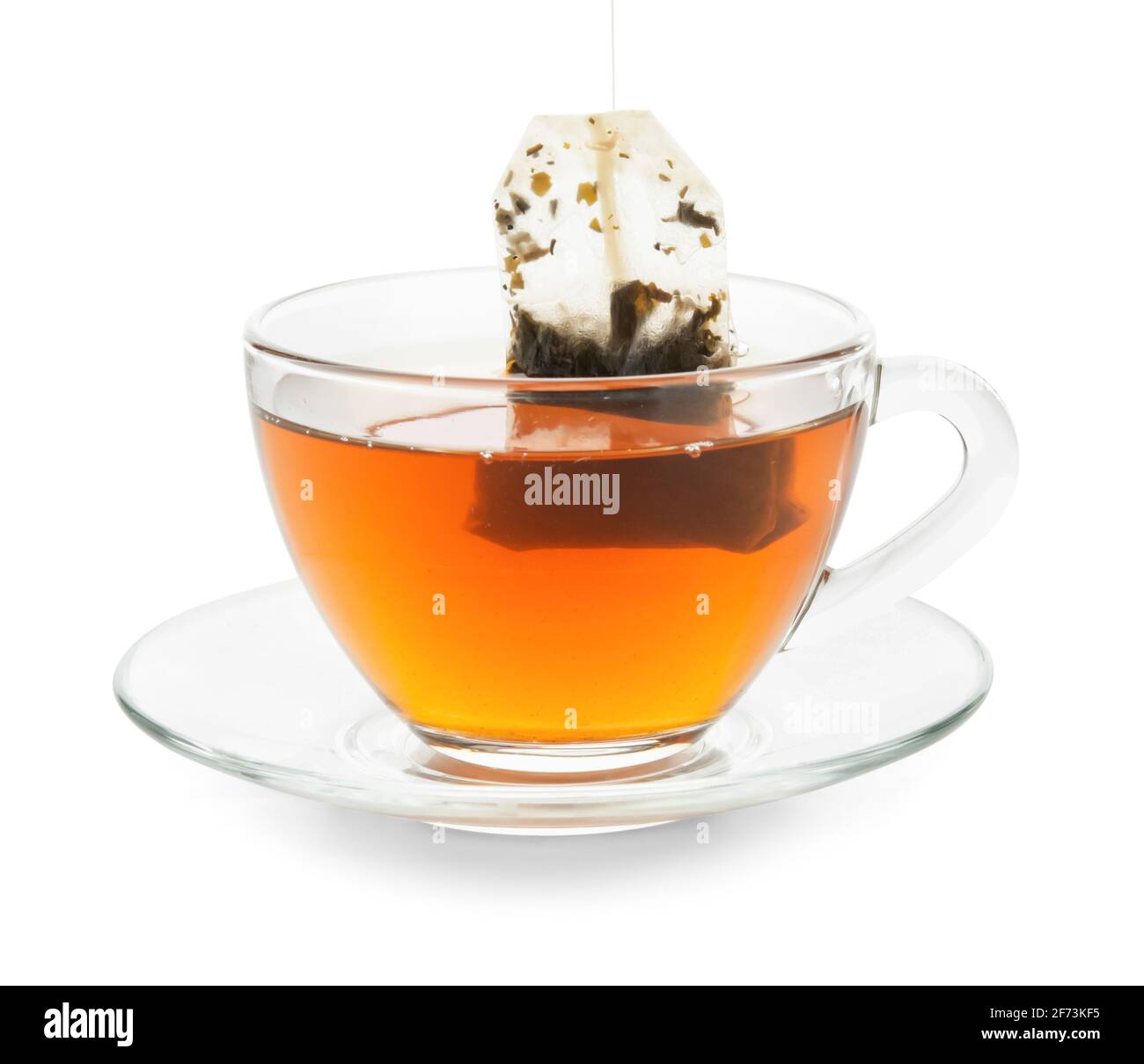 Taking tea bag out of glass cup with hot beverage on white background ...