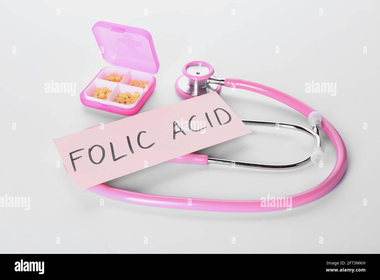 Stethoscope, text FOLIC ACID and container with pills on white ...
