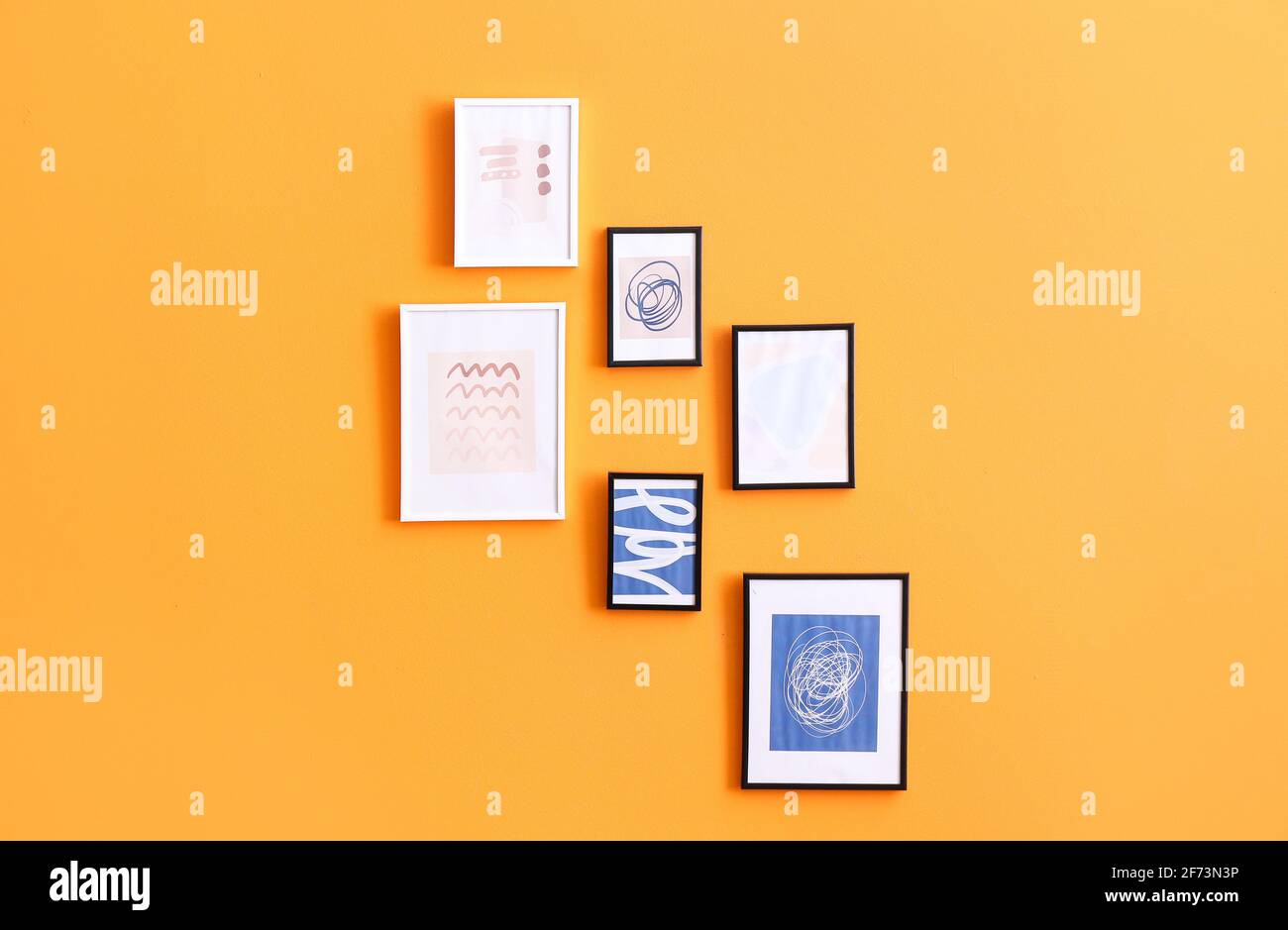 Stylish frames with pictures hanging on color wall Stock Photo - Alamy
