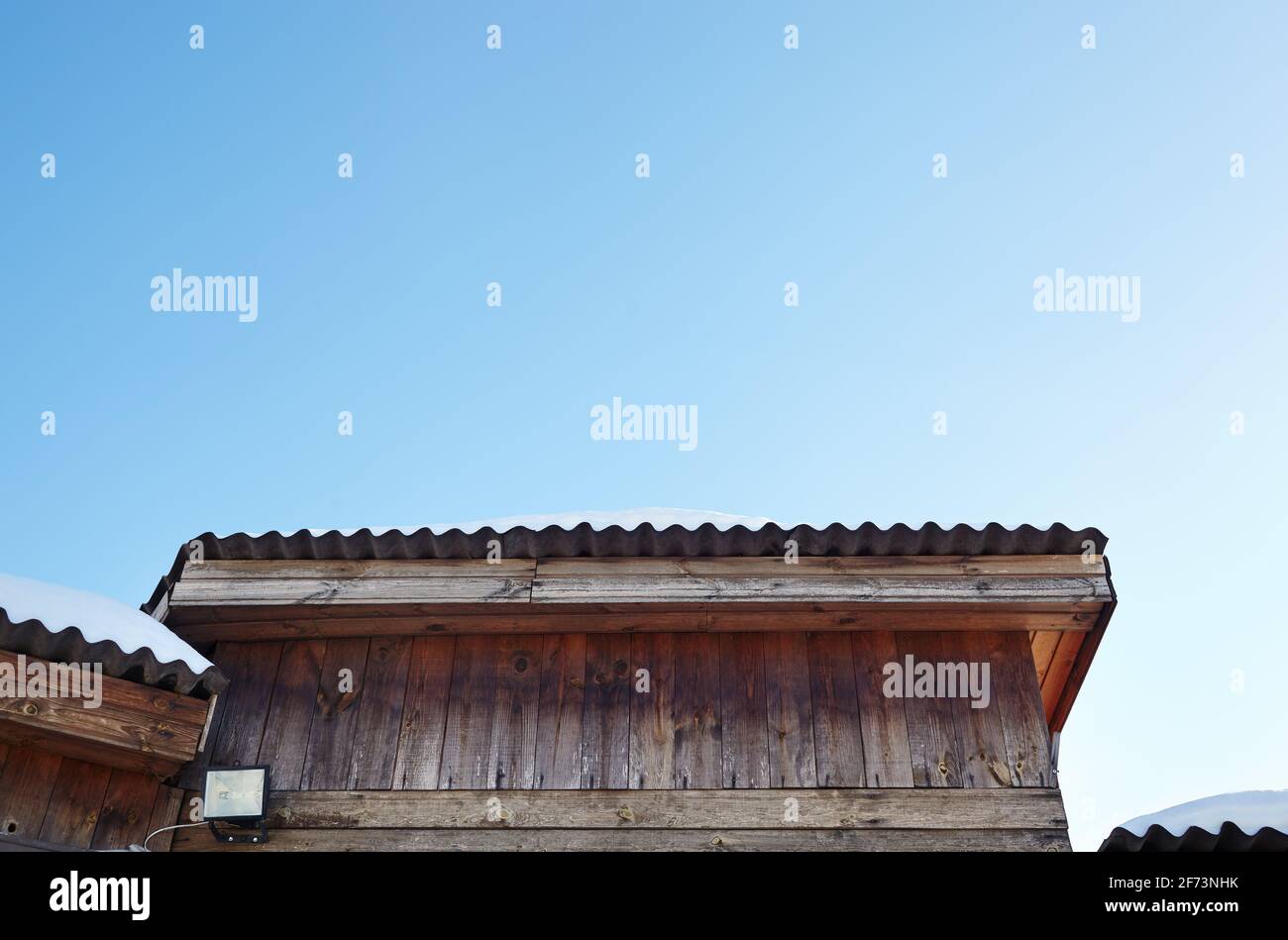 A snow-covered roof of a wooden house. Wooden block building with lots ...