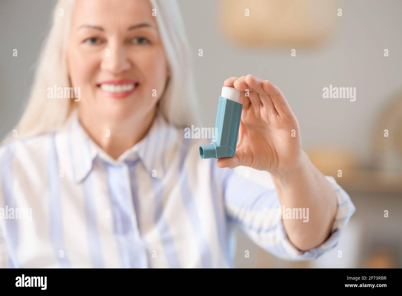 Mature woman with inhaler at home Stock Photo - Alamy