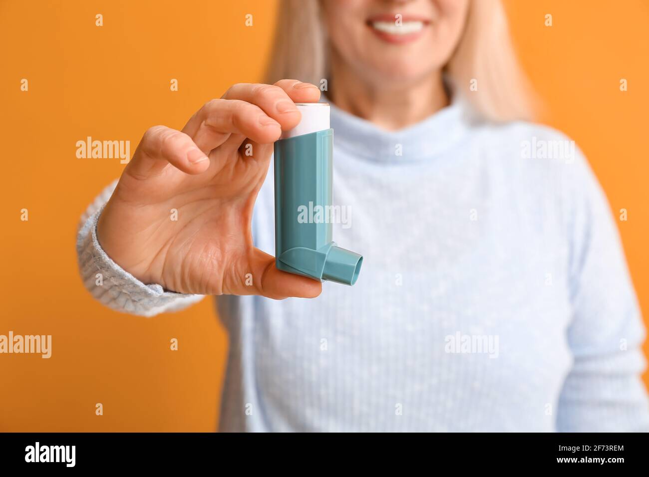Mature woman with inhaler on color background Stock Photo - Alamy