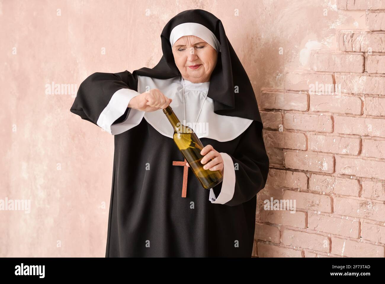 Senior nun with alcohol near color wall Stock Photo - Alamy