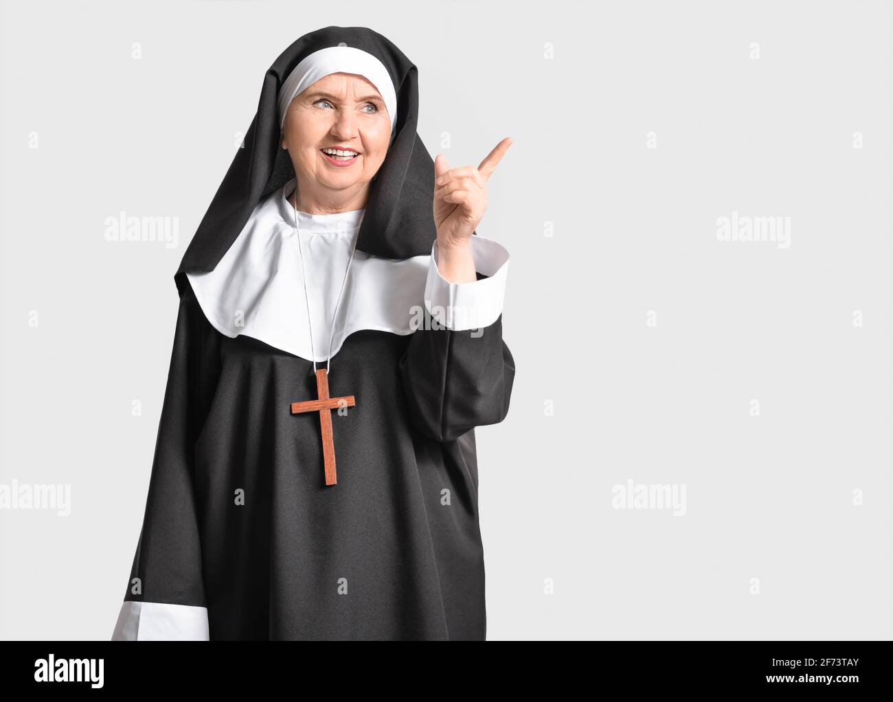 Senior nun pointing at something on light background Stock Photo - Alamy