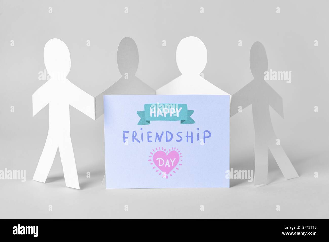 Paper human figures and greeting card for Friendship Day on grey ...