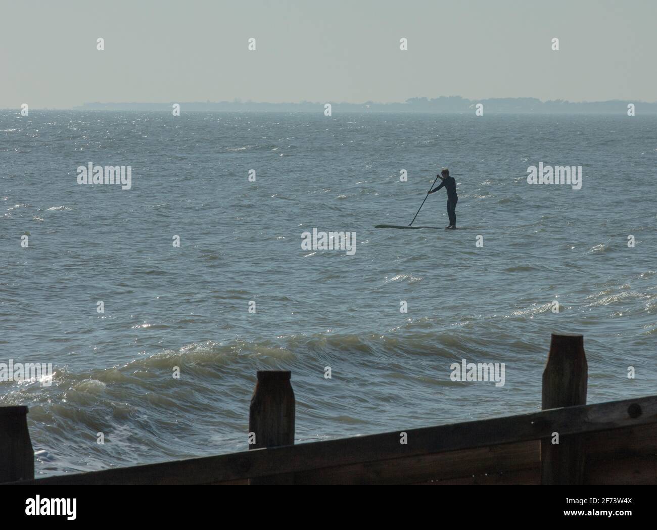 Paddle boarder seen just of the beach on the south coast of England, UK ...