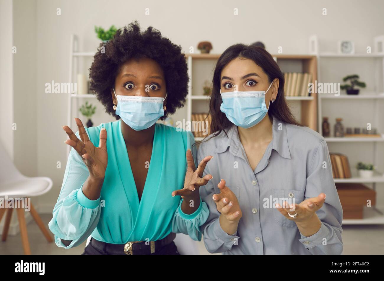 Webcam portrait of two funny surprised young women in face masks ...