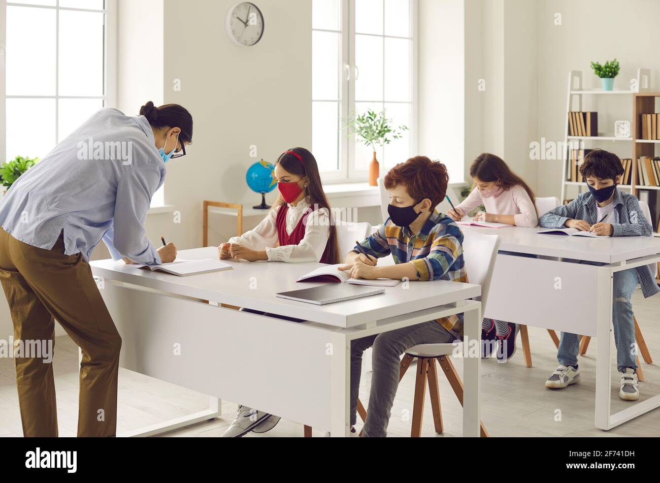 Kids and teacher following Covid-19 precautions wearing medical face ...