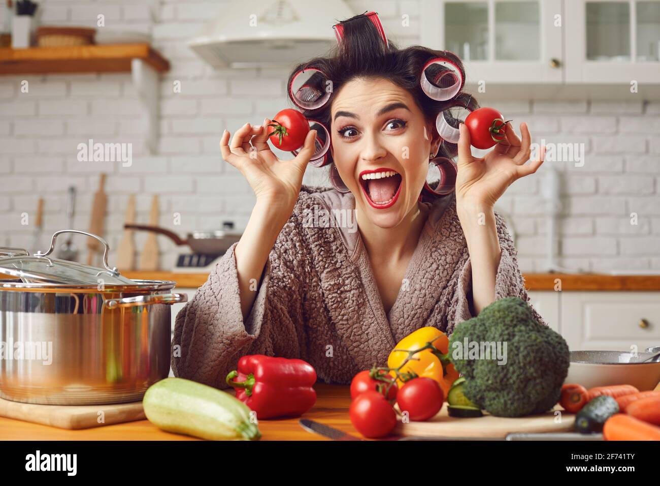 Happy young woman having fun while cooking healthy vegetarian meal in ...