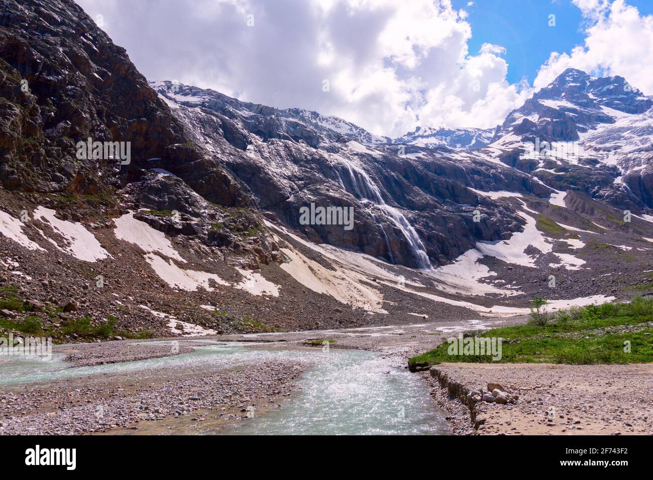 View of snow glaciers with a waterfall and a river in a mountain valley ...
