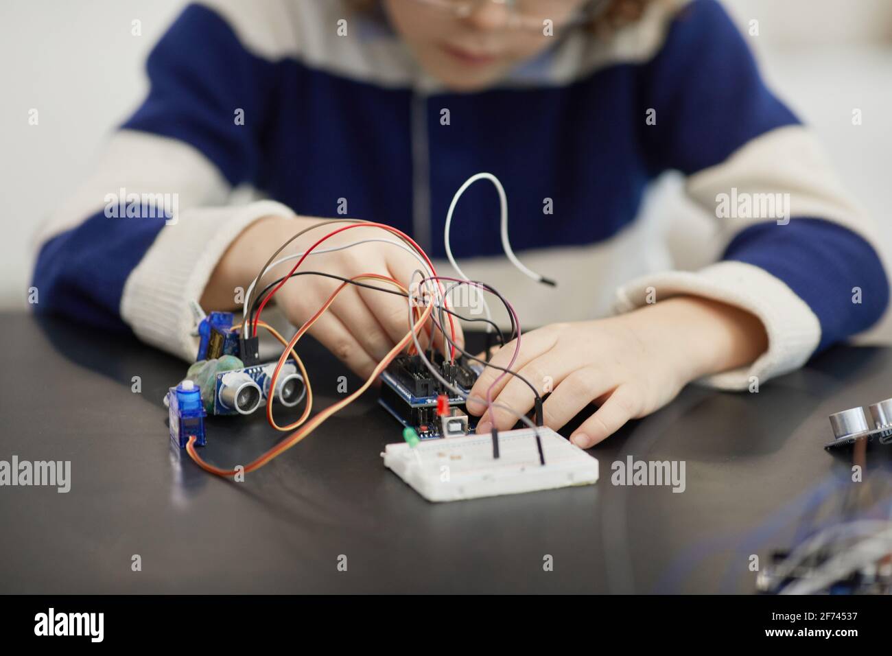 Close up of unrecognizable child experimenting with electric circuits while building robots ...