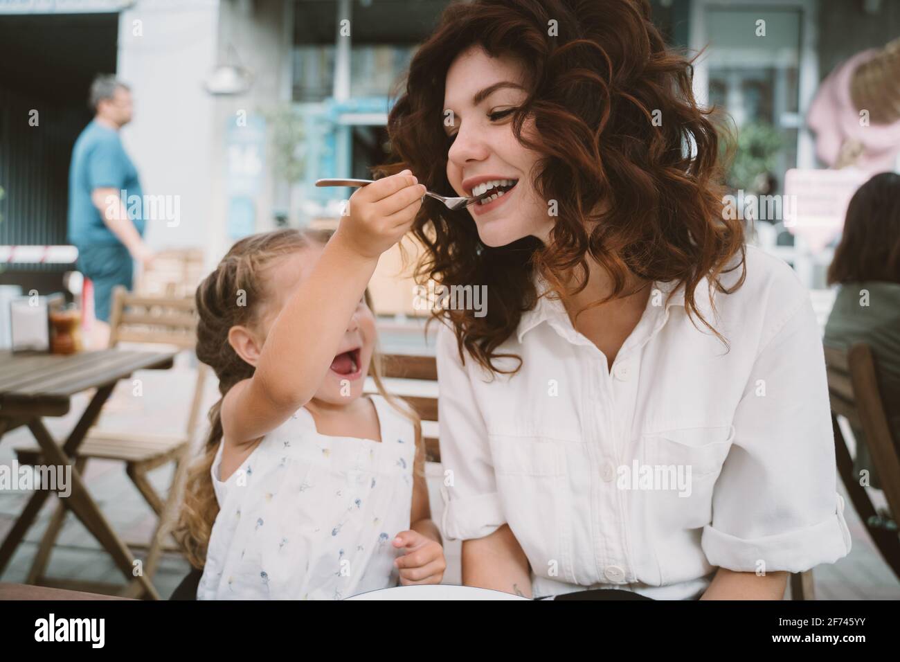 Young mom eating cake with smiling kid on the street Stock Photo - Alamy