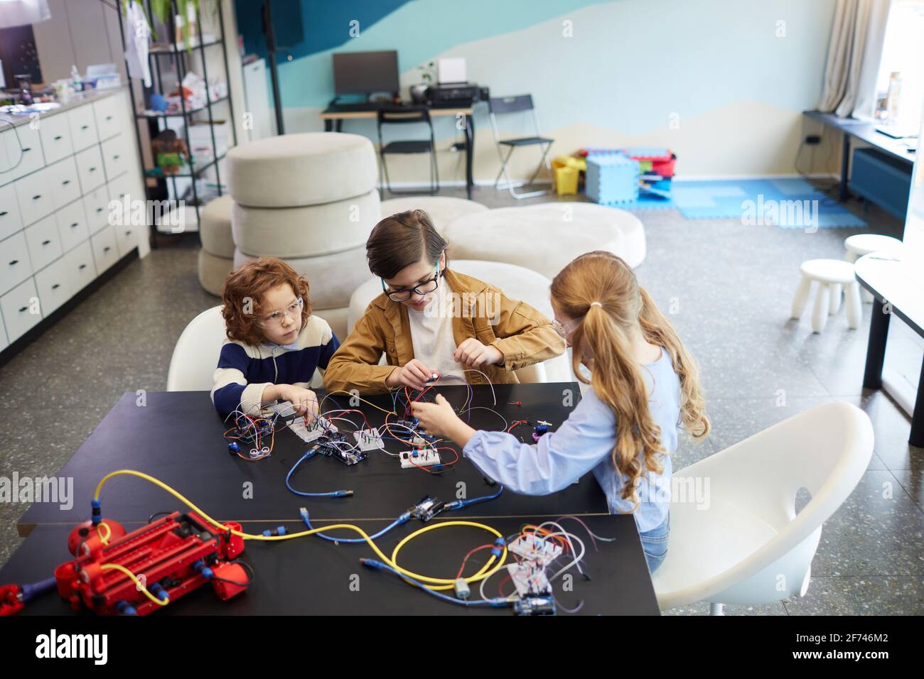 High angle view at group of children building robots and experimenting with electric circuits in ...