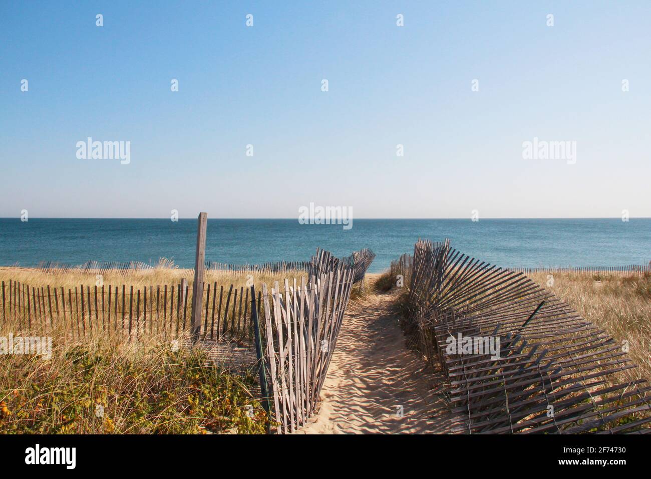 Secluded sandy trail path walkway with old weathered wood fence and sea ...