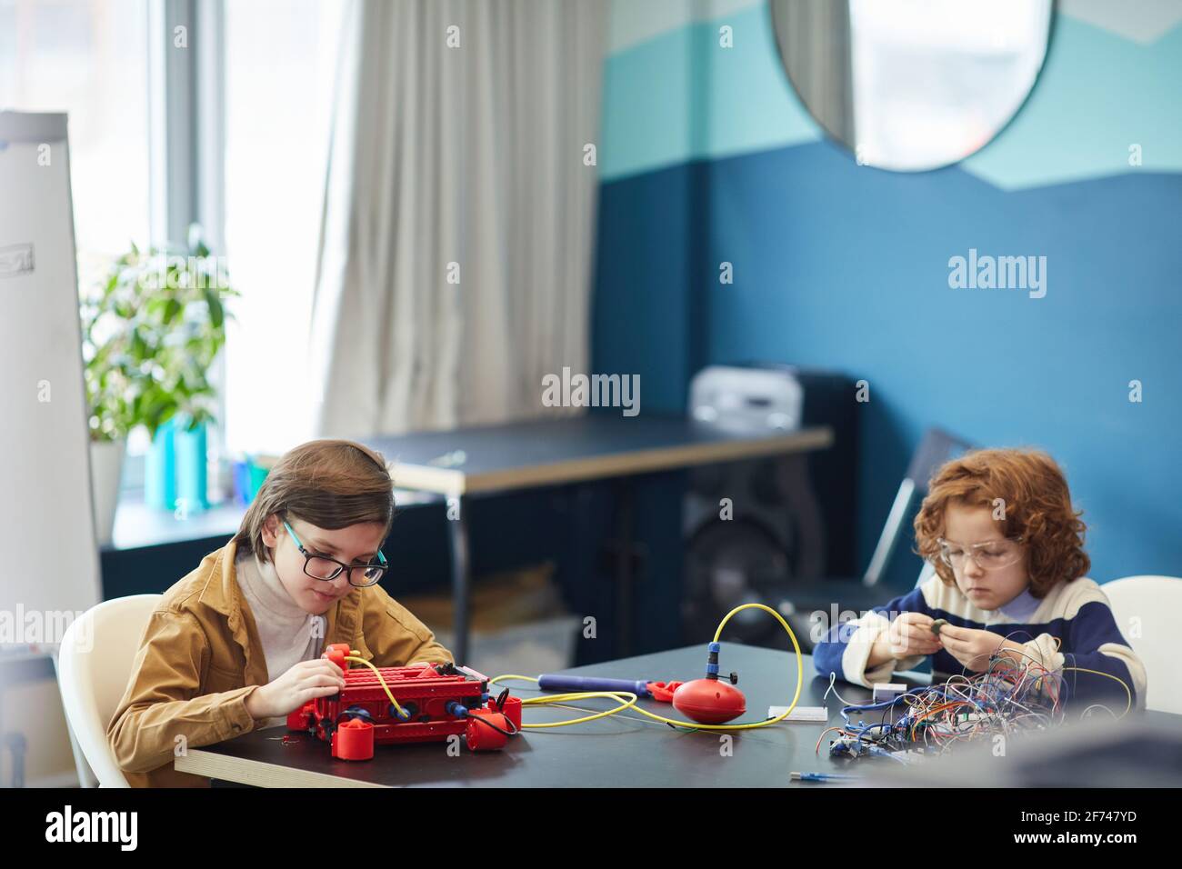Wide angle portrait of two boys building robots while enjoying ...