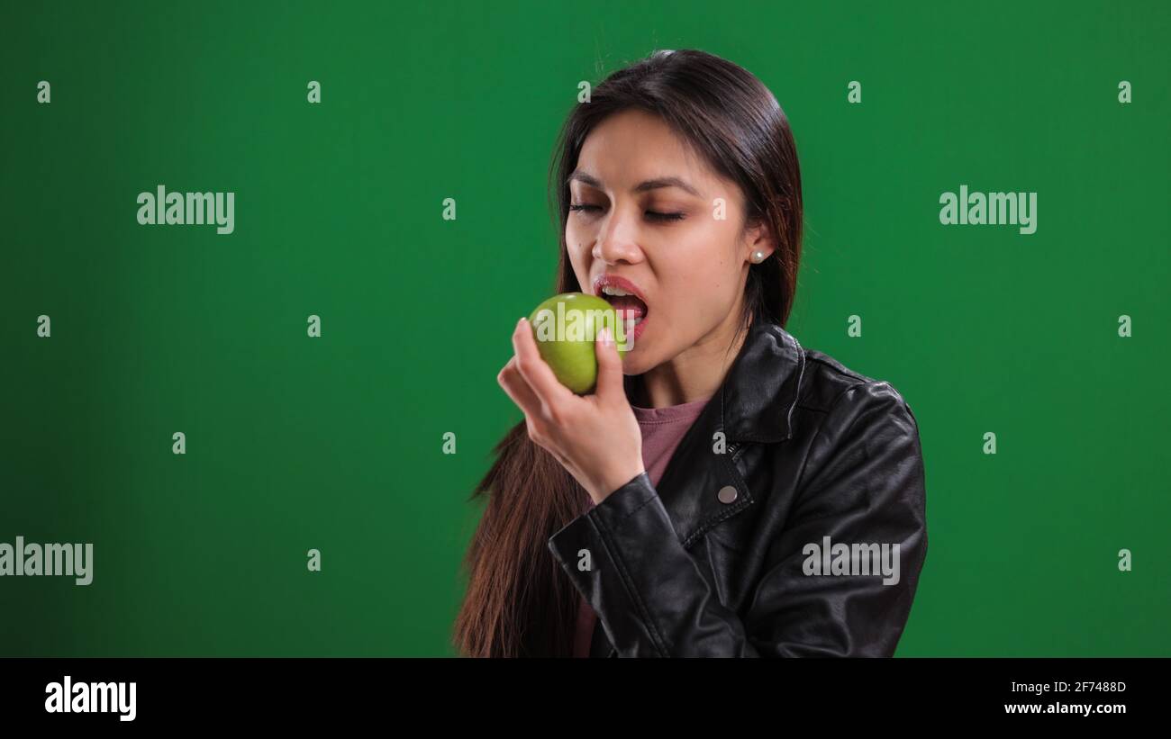 Young woman bites into a green apple Stock Photo - Alamy