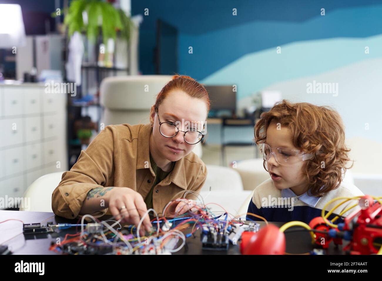 Portrait of female teacher helping boy building robot during ...
