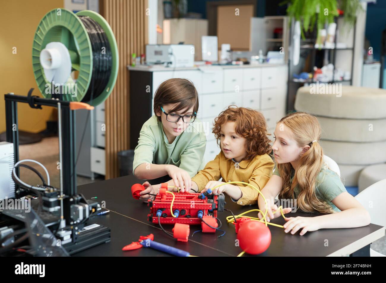 High angle portrait of three children building robot boat together ...