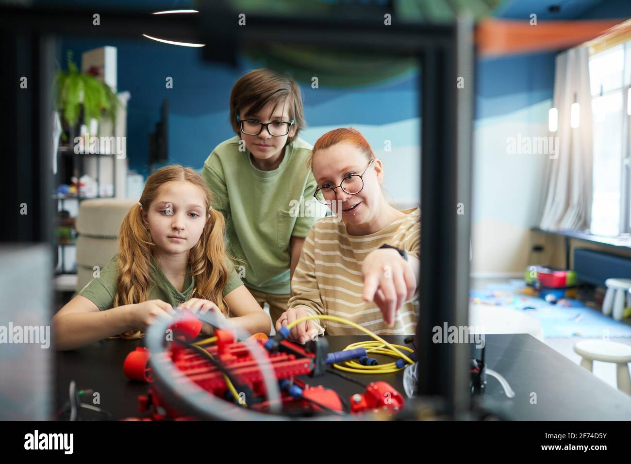 Front view portrait of female teacher pointing at 3D printer during ...