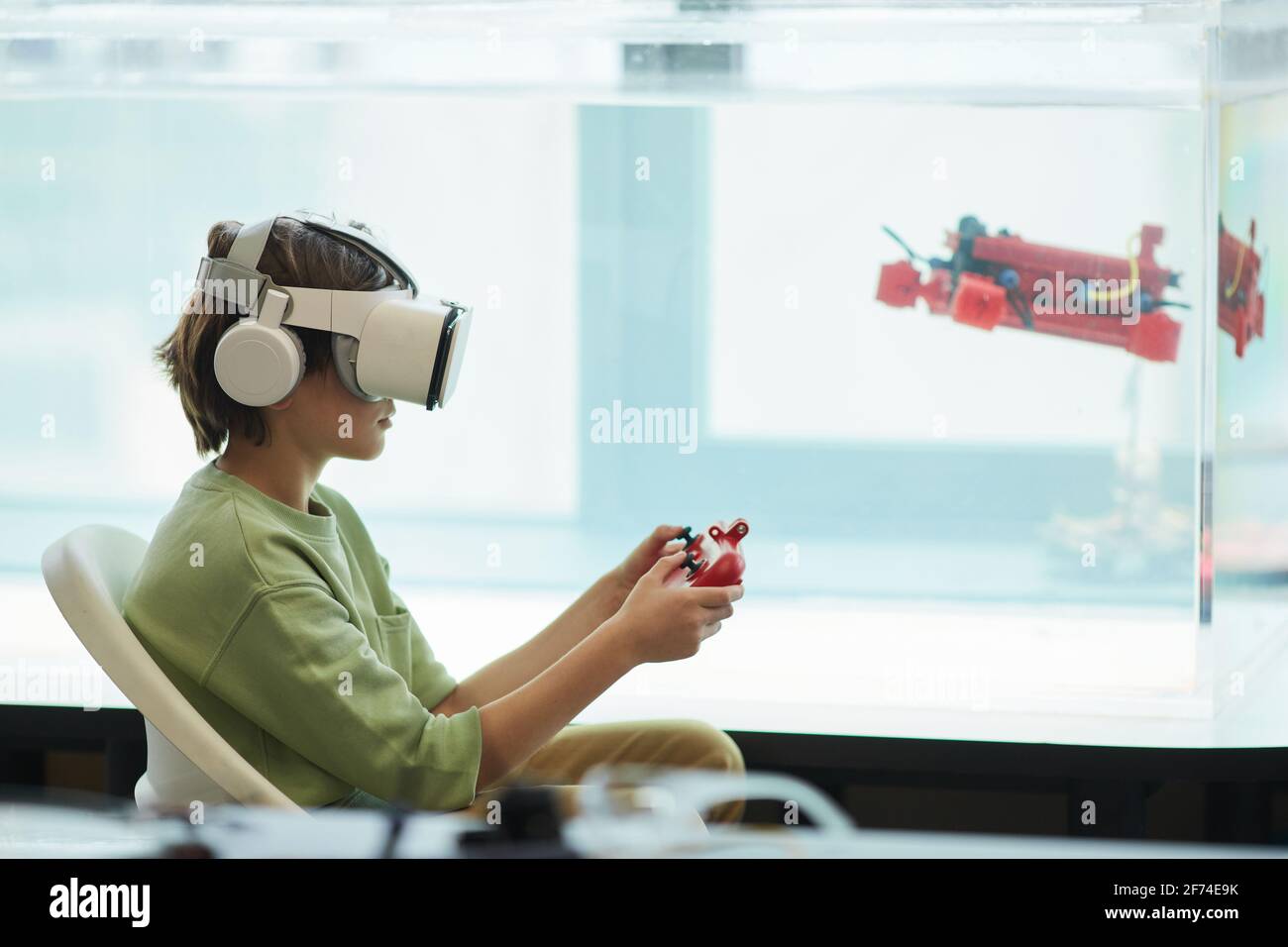 Side view portrait of boy wearing VR headset while operating robotic ...
