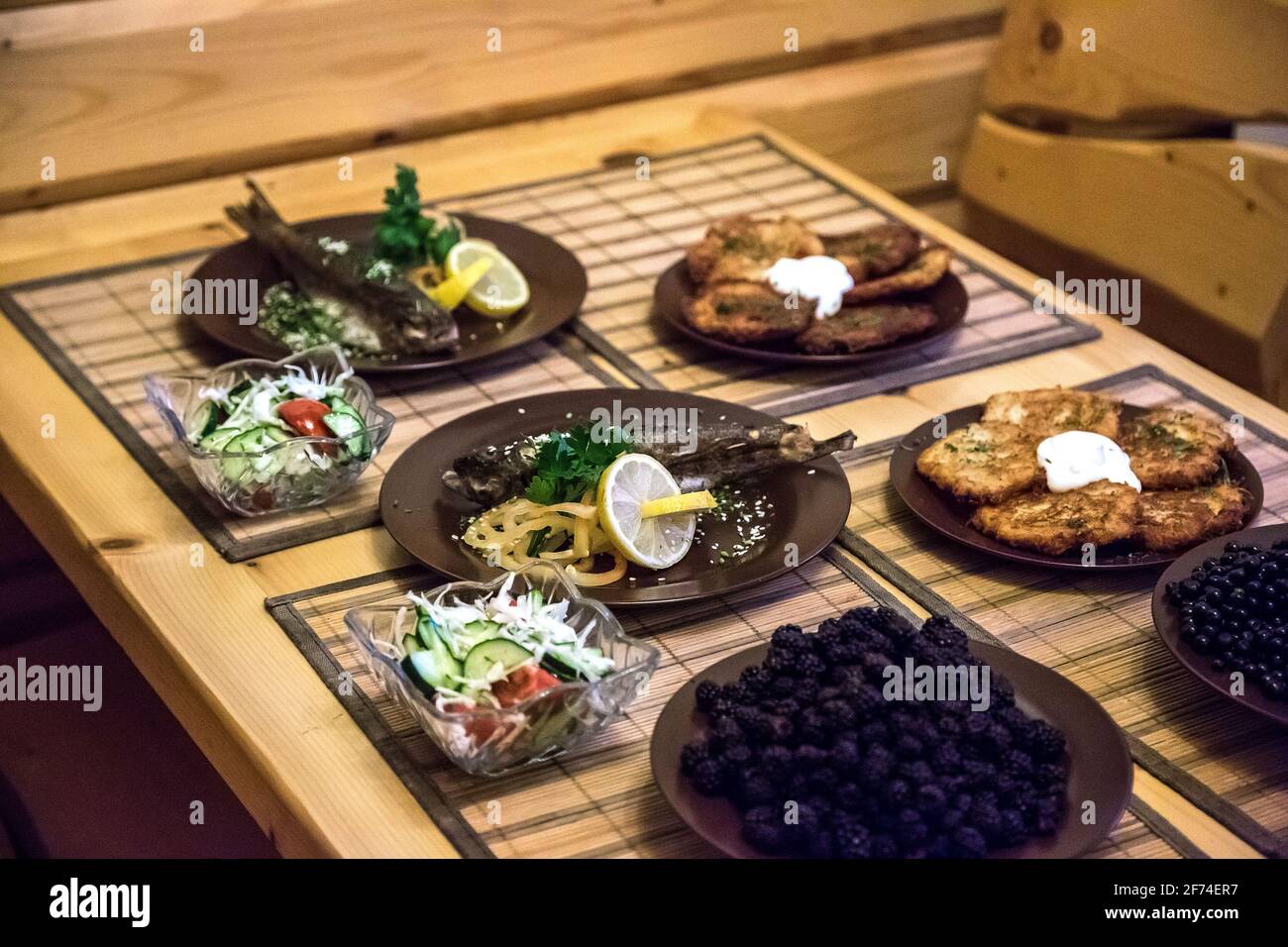 Fried fish with lemon, potato pancake, blackberry in traditional dish ...