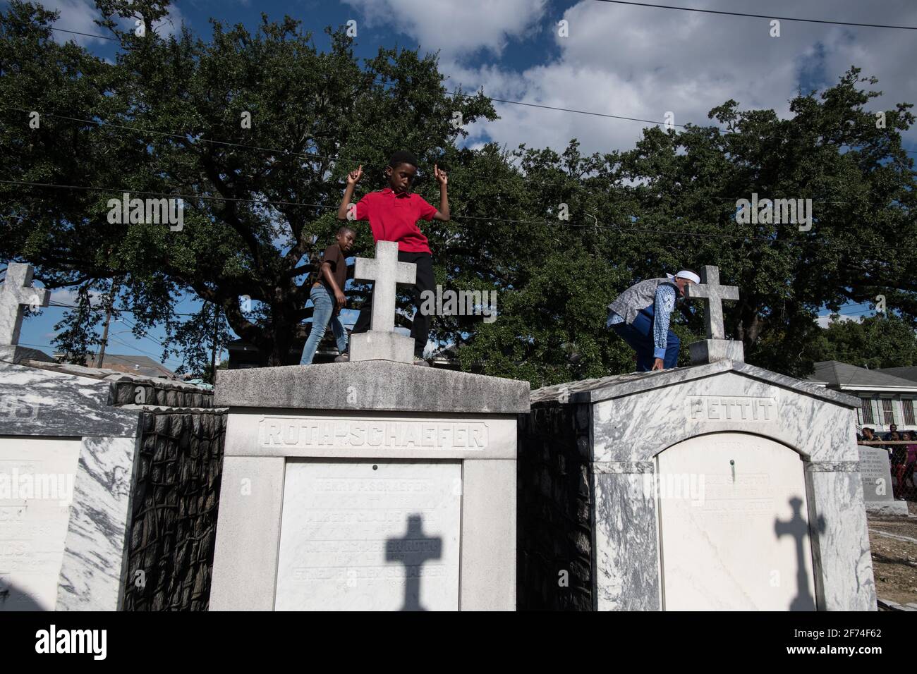 Young men dance atop tombs during a vibrant second line procession ...