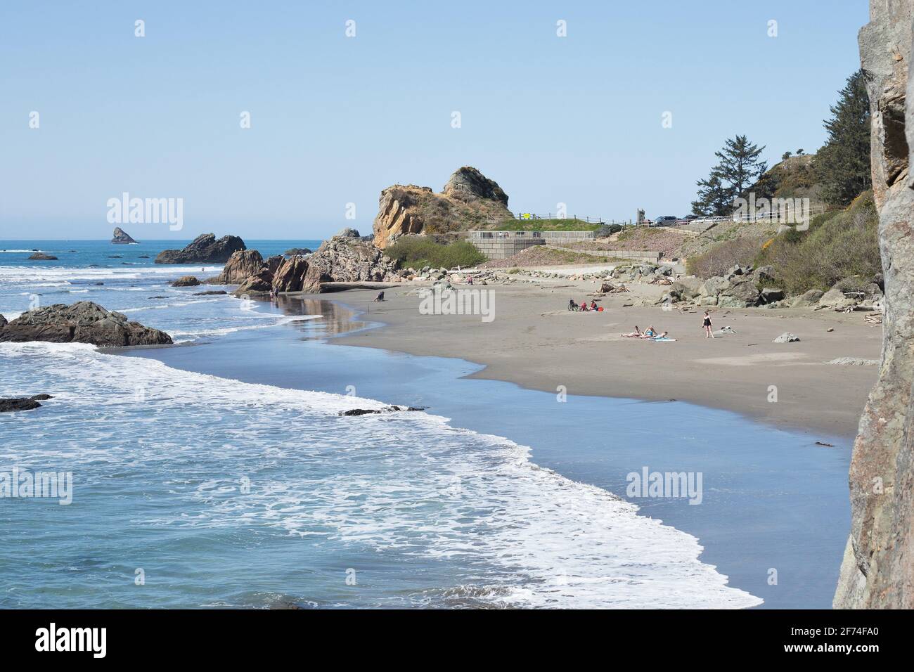 People sunbathing on the beach as seen from a distance, at Harris Beach ...