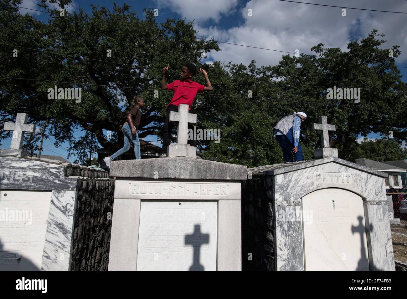 Young men dance atop tombs during a vibrant second line procession ...