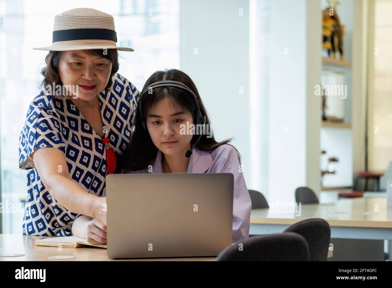 Asian mother with computer notebook teaching daughter to learn or study ...