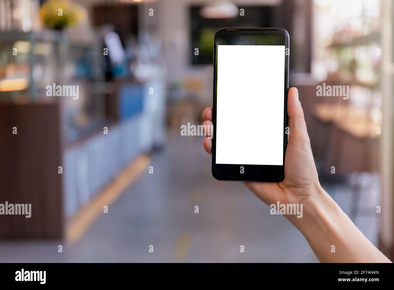 Hand women holding black mobile phone with blank white screen with blur ...