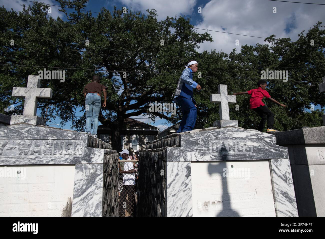Young men dance atop tombs during a vibrant second line procession ...