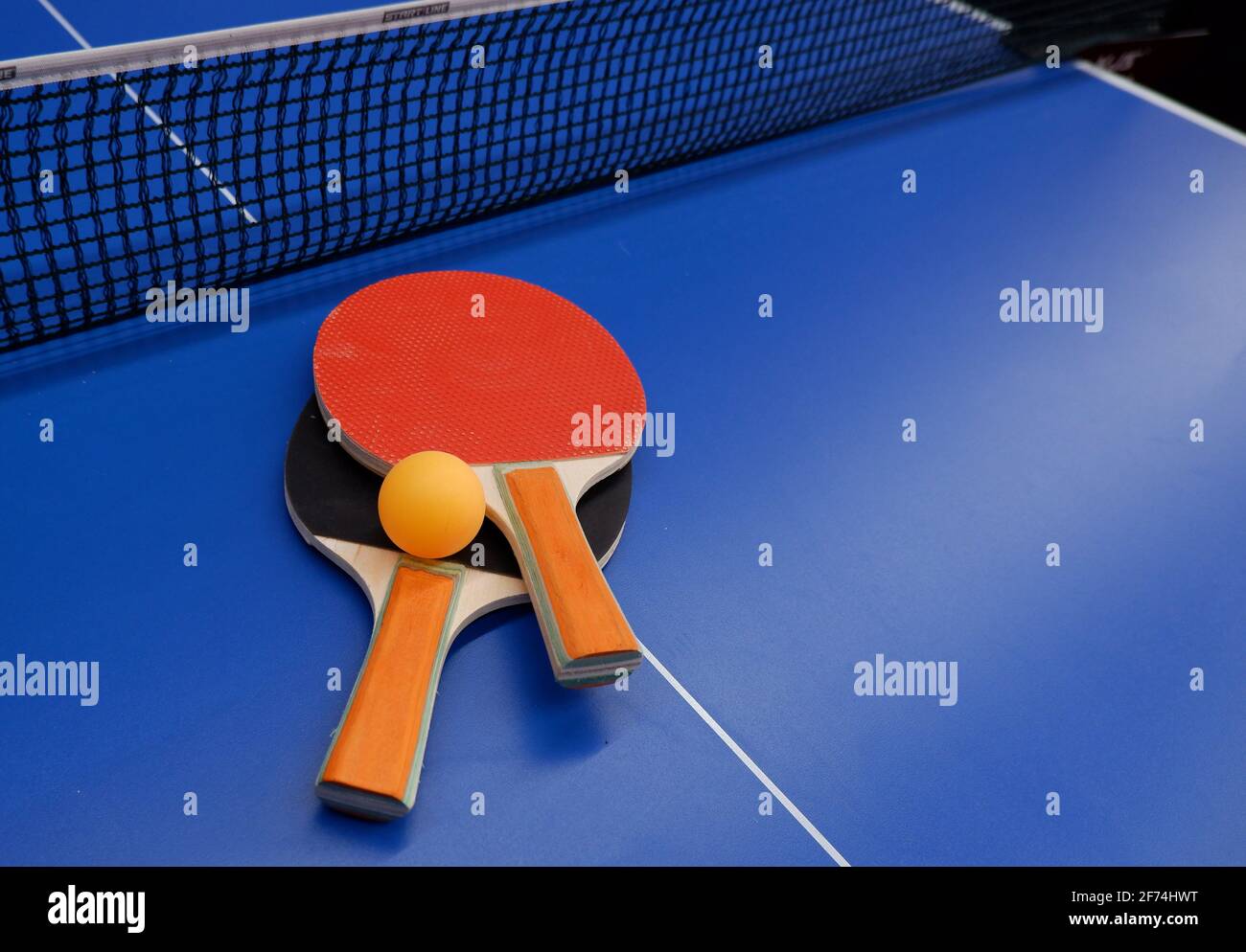 on the tennis table is a ball and two table tennis rackets Stock Photo ...