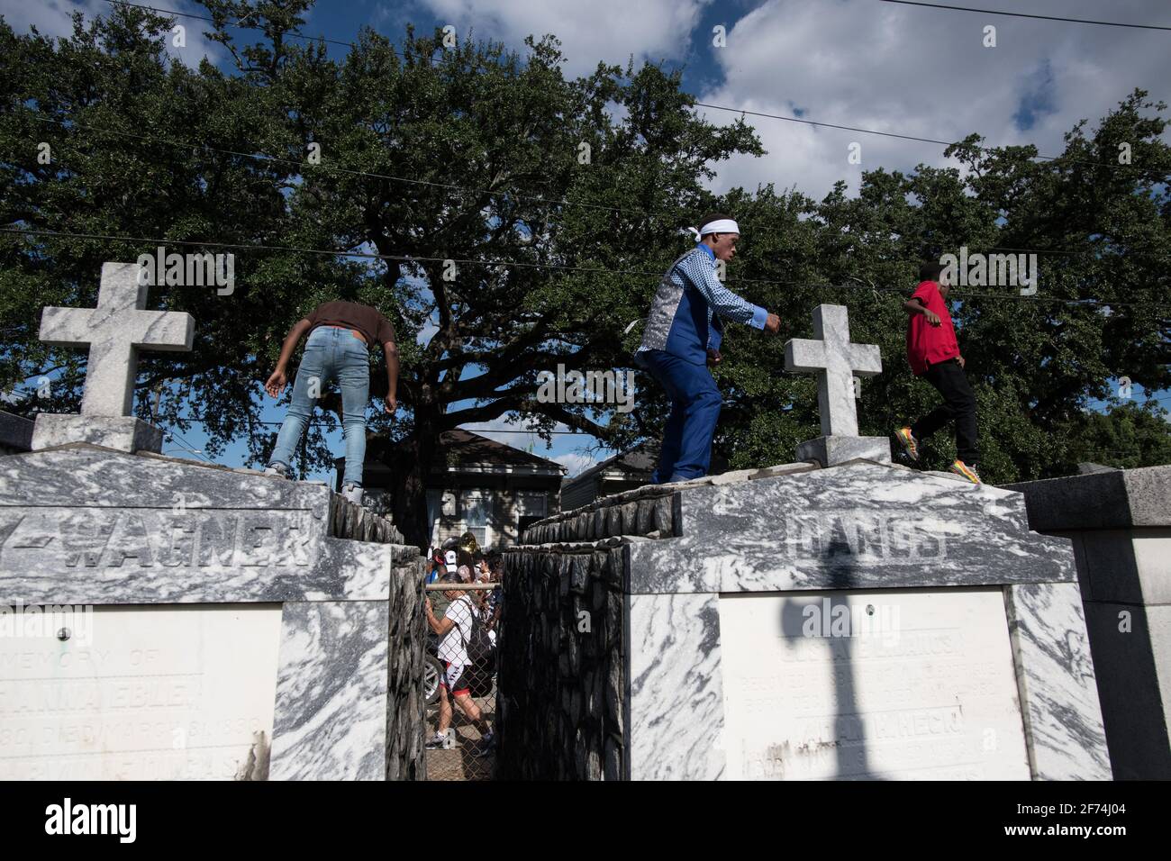 Young men dance atop tombs during a vibrant second line procession ...