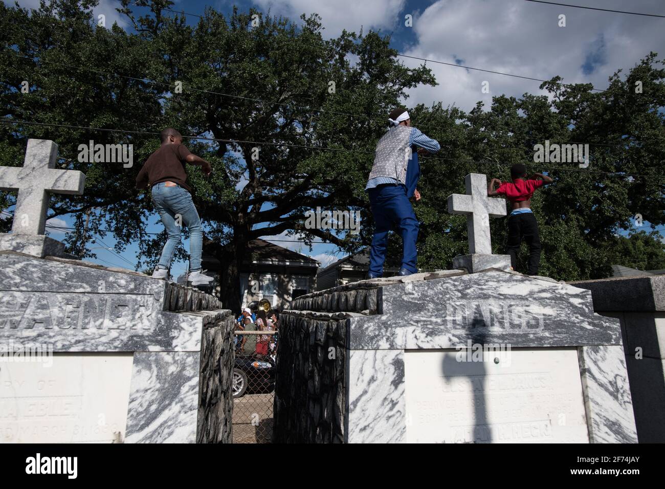 Young men dance atop tombs during a vibrant second line procession ...