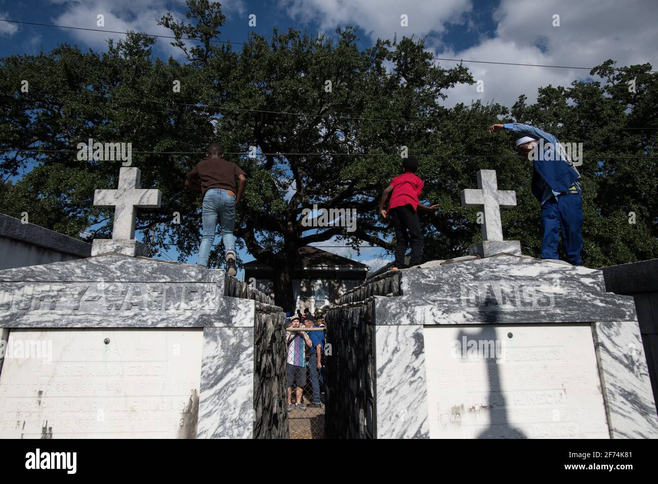 Young men dance atop tombs during a vibrant second line procession ...