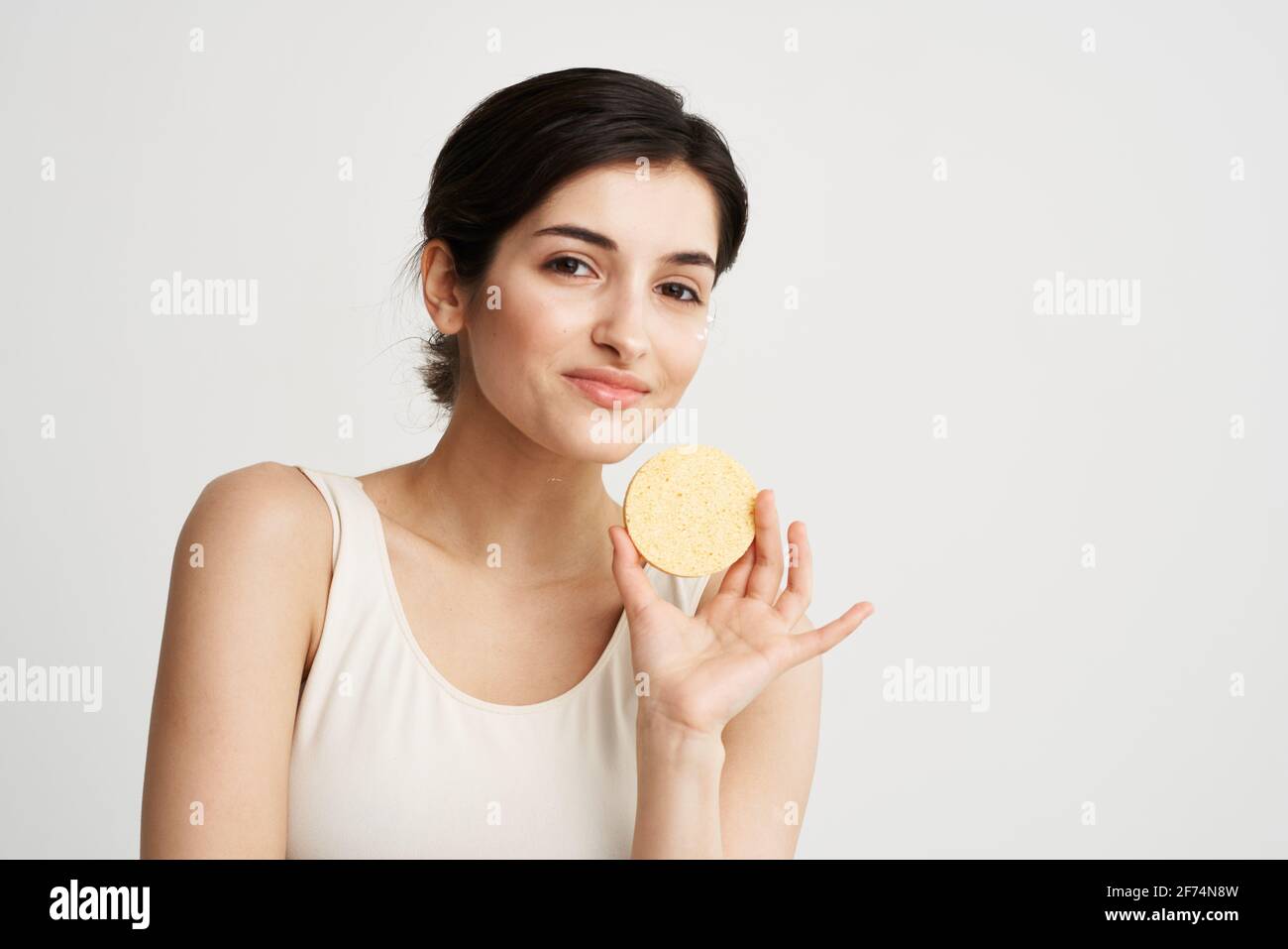 Cheerful pretty woman with a sponge in her hands skin care cosmetics ...