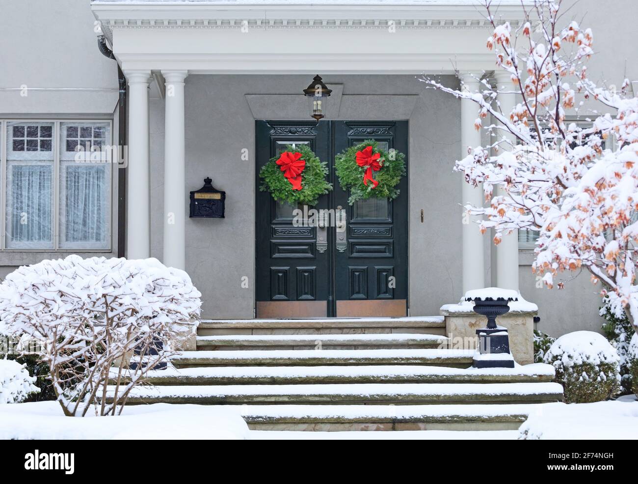 Christmas wreath on double front door of snow covered house Stock Photo ...