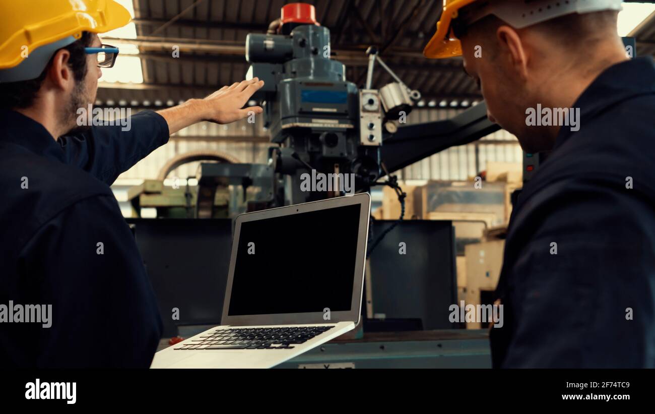 Skillful factory worker working with laptop computer to do procedure ...