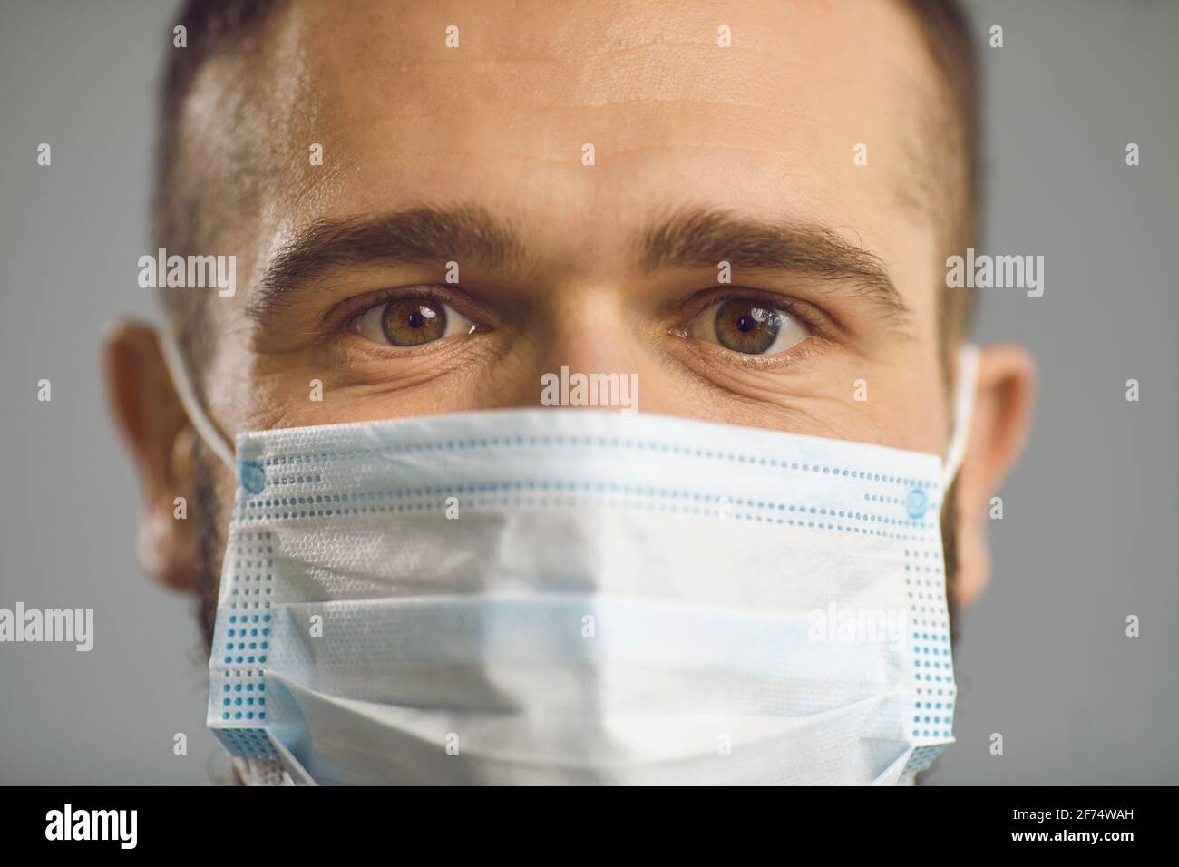 Closeup portrait of man in face medical mask with wide-open surprised ...