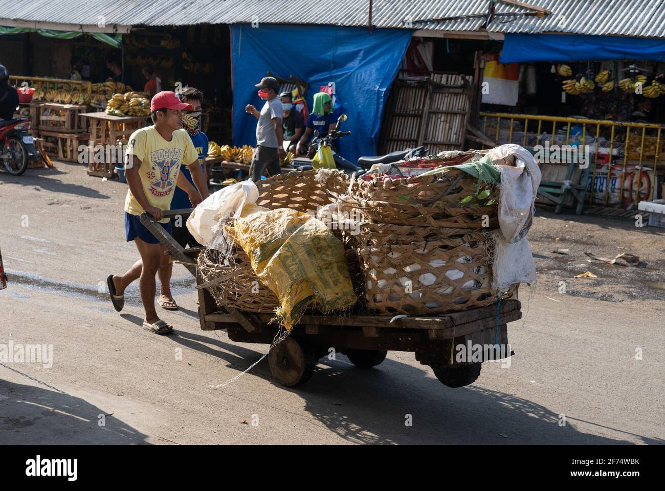 A man pushing a wooden cart with baskets in a market area, Cebu City ...