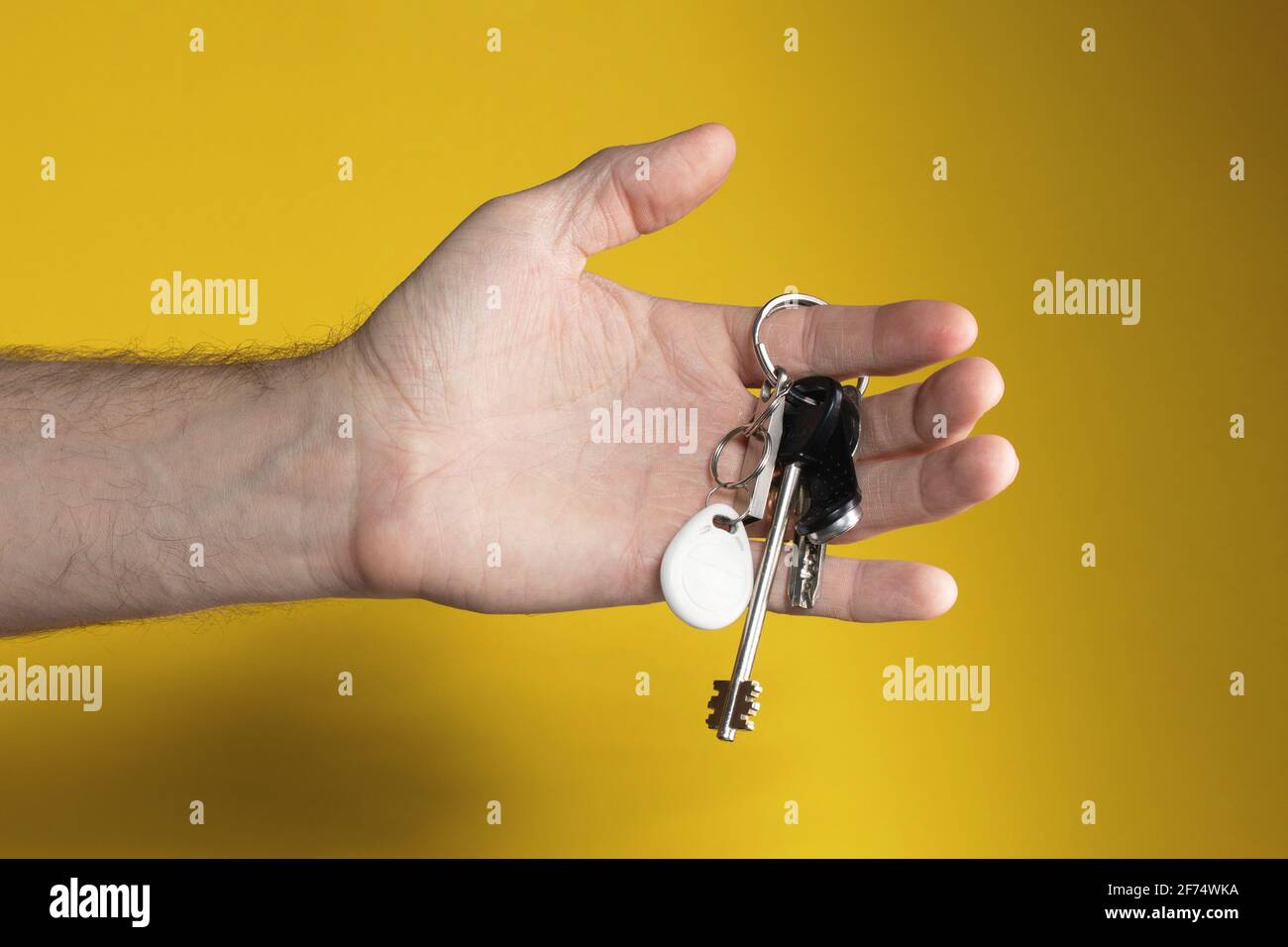Hand holding key chain on yellow background. Building concept Stock ...