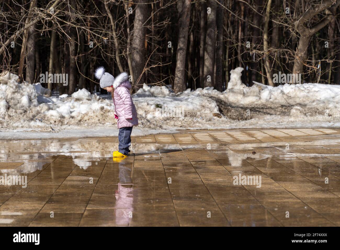happy funny child girl playing in the spring puddles and laughing Stock ...