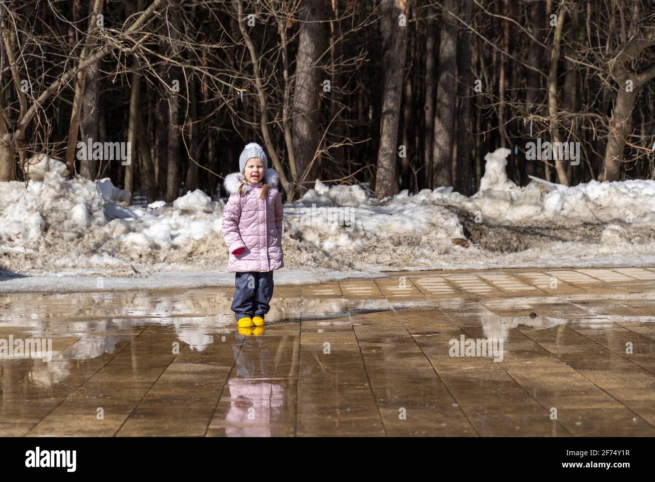 happy child girl jumping on spring puddles and laughing Stock Photo - Alamy