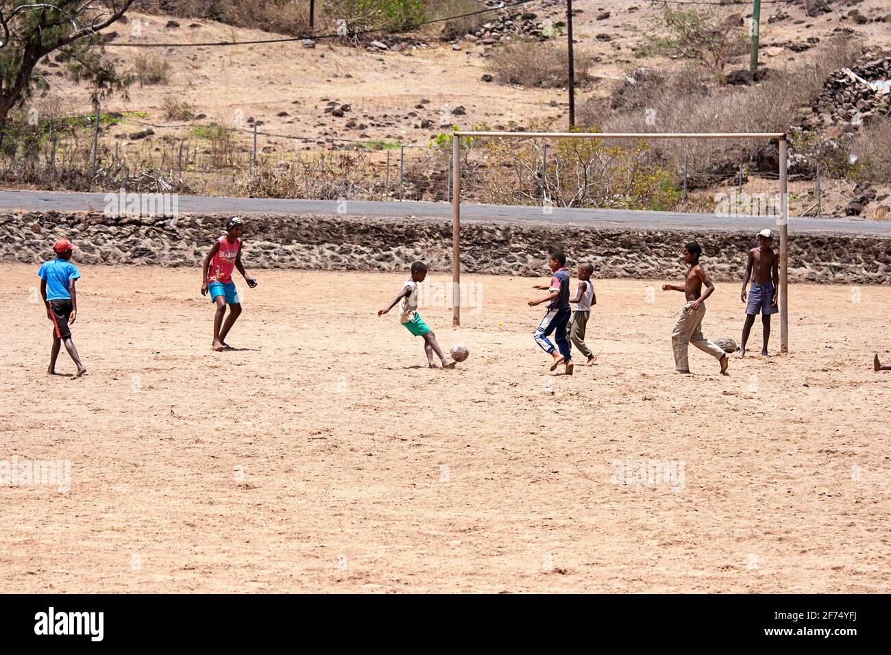 Local boys playing football or soccer on a basic football pitch on ...