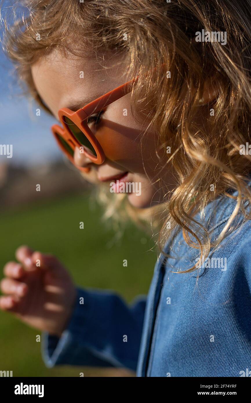 Side view of cute happy little girl in trendy clothes and sunglasses ...