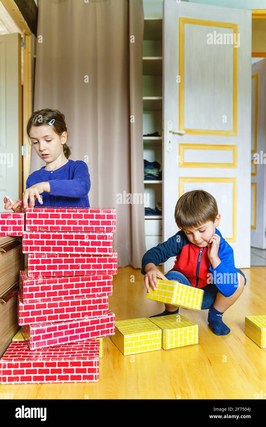 Side view of children playing building with cardboard pieces at home ...