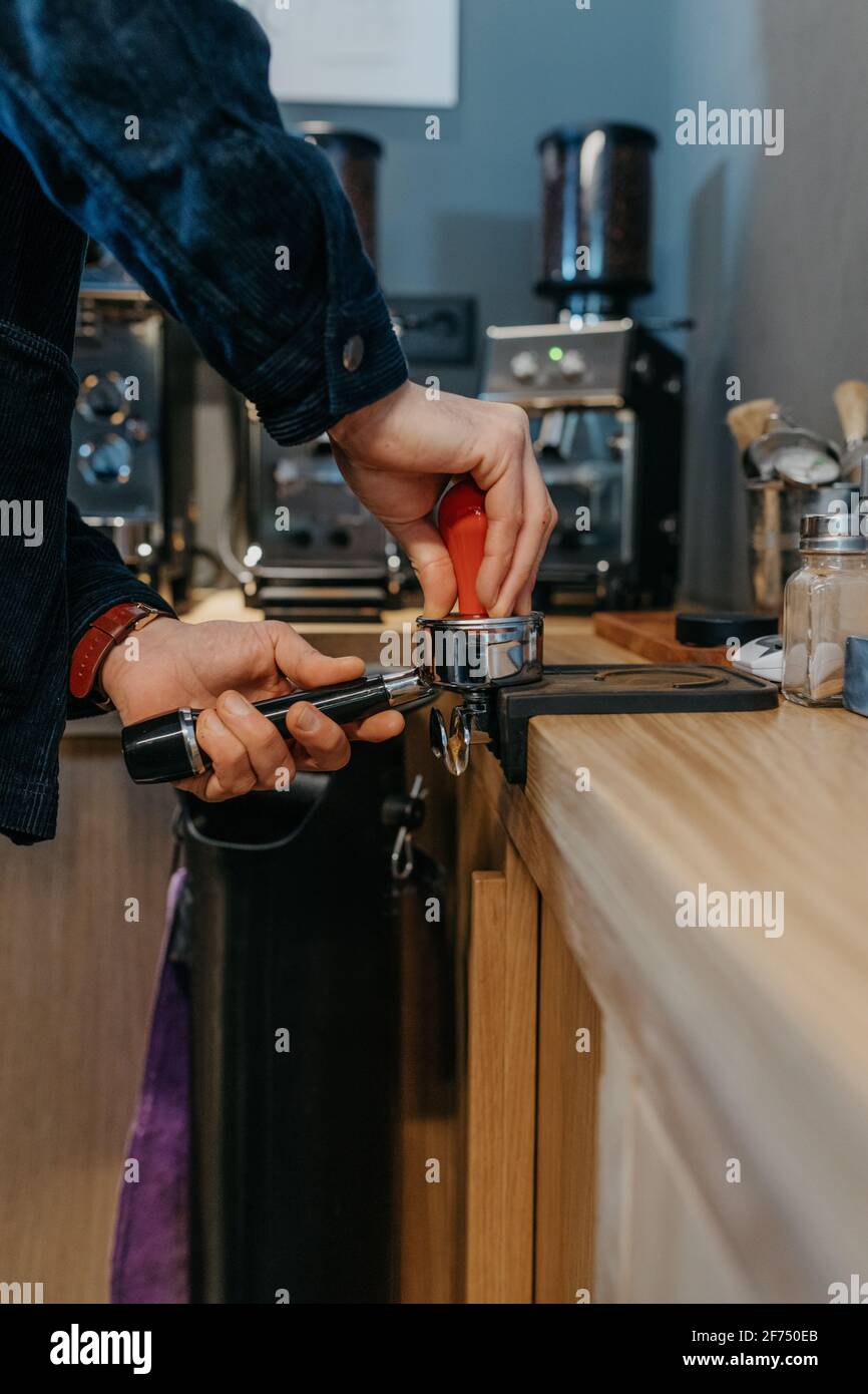 Crop faceless barista standing at table and preparing fresh aromatic ...