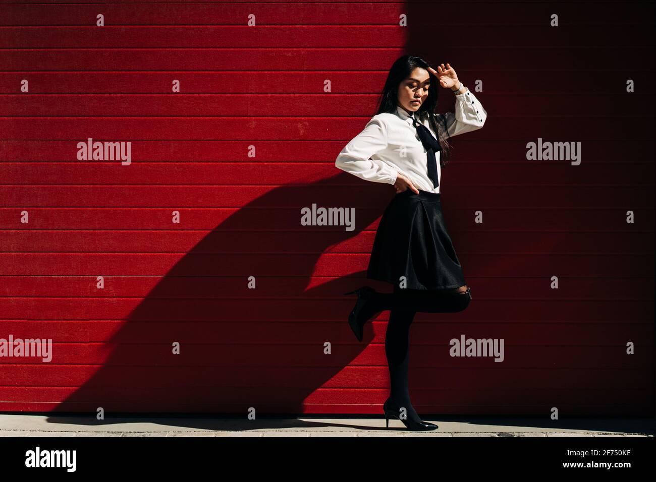 Full body side view of female with hand on waist covering face from ...