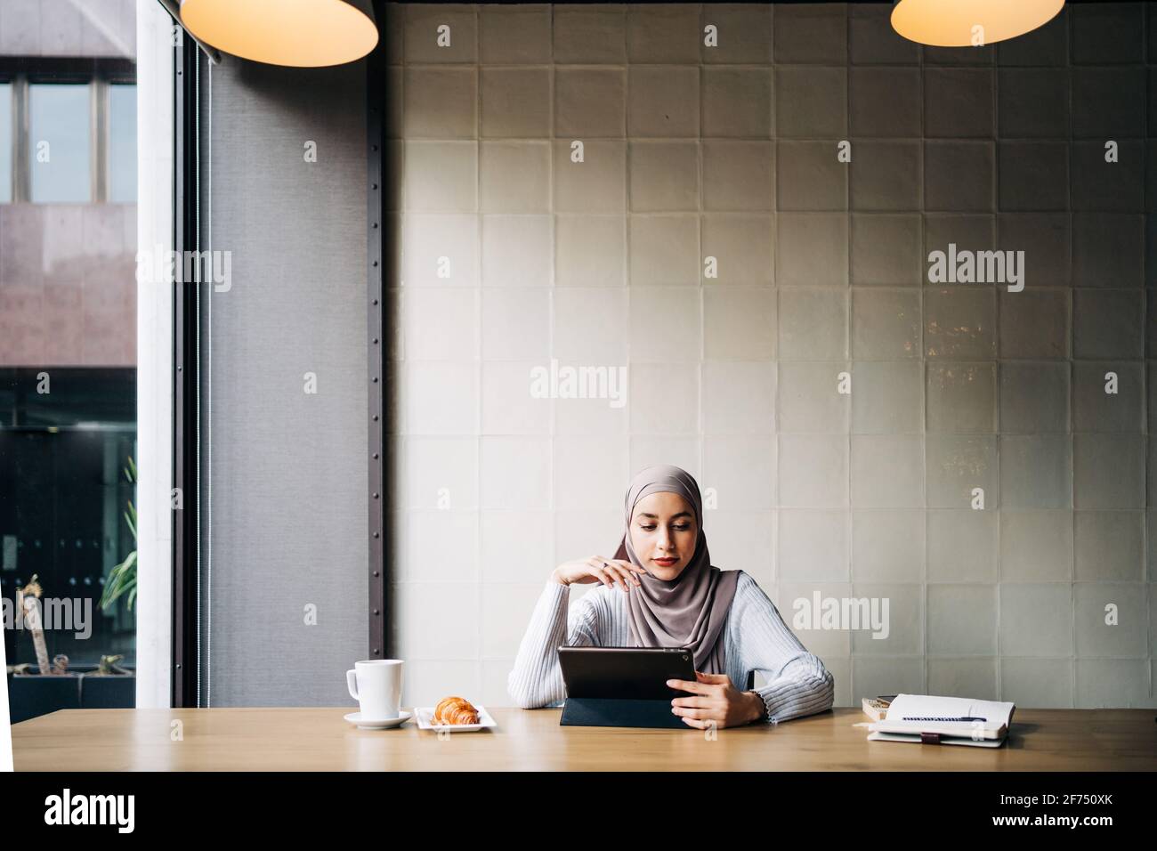 Content Muslim female in hijab and talking on video chat via tablet ...
